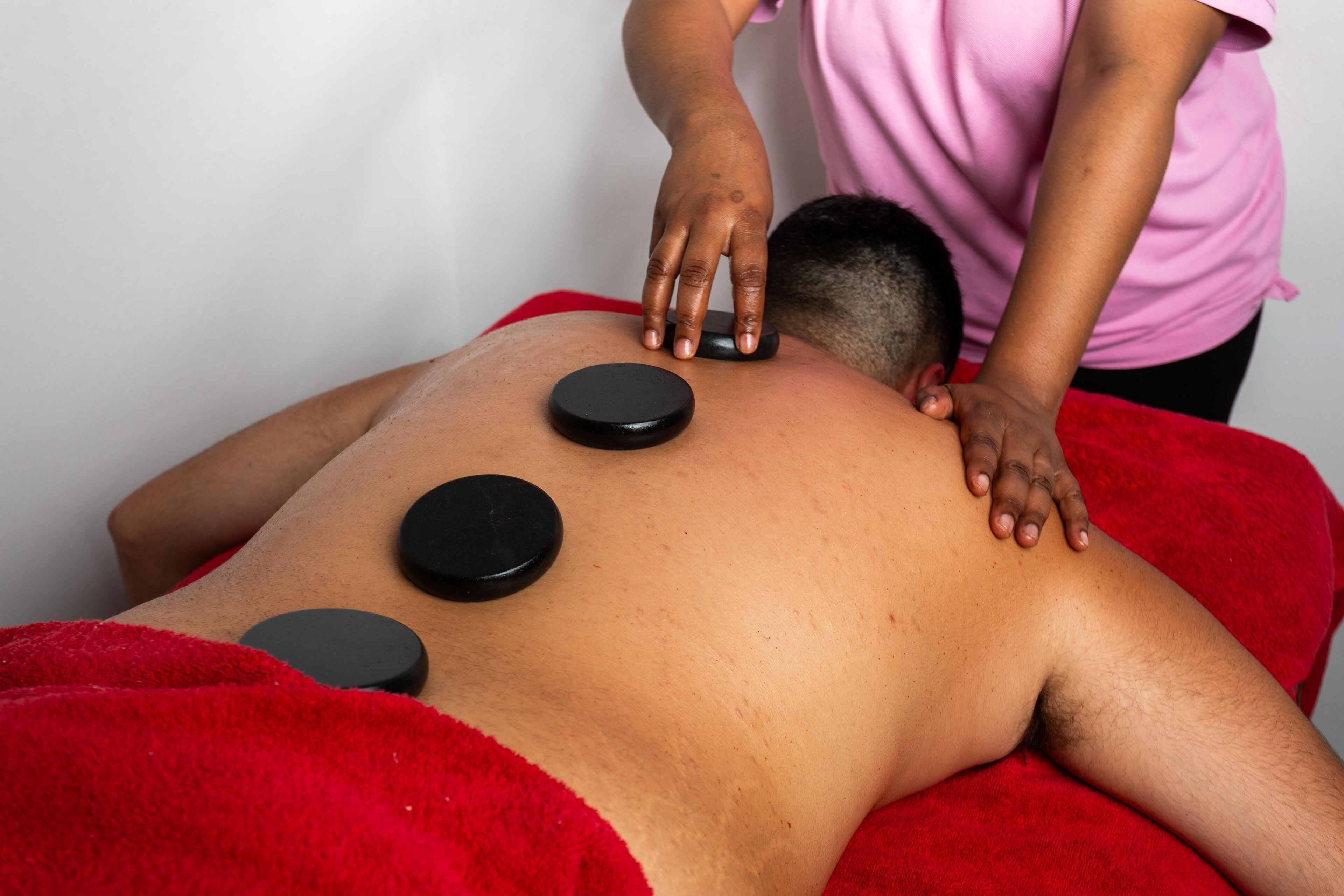 Uma pessoa recebendo uma massagem nas costas com três objetos circulares pretos.