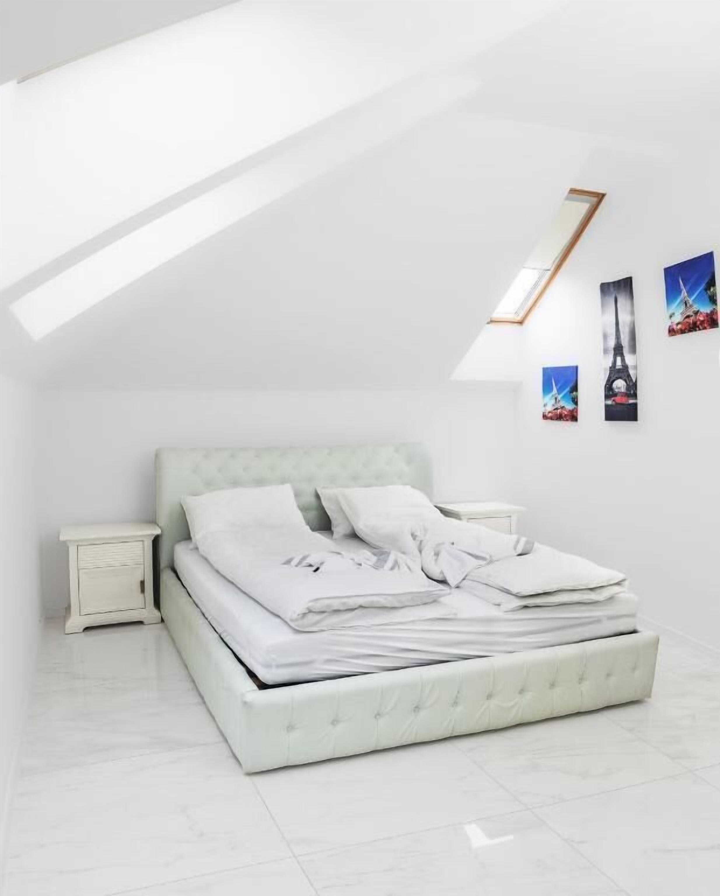 Quarto com uma cama, uma mesinha de cabeceira e três quadros na parede.