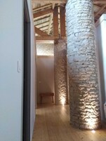 Um corredor com um pilar de pedra, vigas de madeira e um banco.