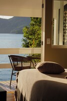 Um quarto com cama, uma cadeira e vista para um lago.