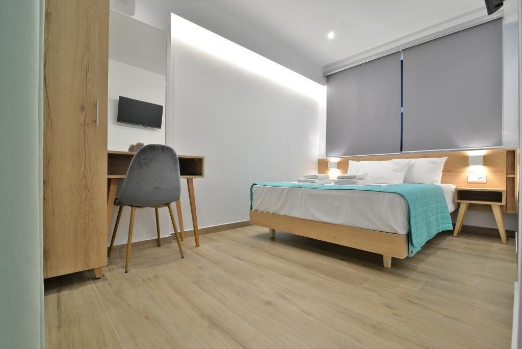 Quarto moderno com cama, mesas de cabeceira, escrivaninha e uma cadeira.