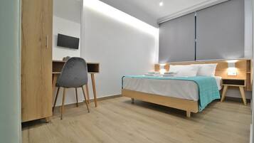Quarto moderno com cama, mesas de cabeceira, escrivaninha e uma cadeira.