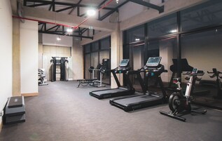 Uma academia com esteiras, bicicleta ergométrica e aparelhos de musculação.