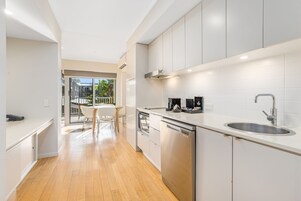 Uma cozinha moderna com armários brancos, eletrodomésticos de aço inoxidável e uma janela grande que traz luz natural.