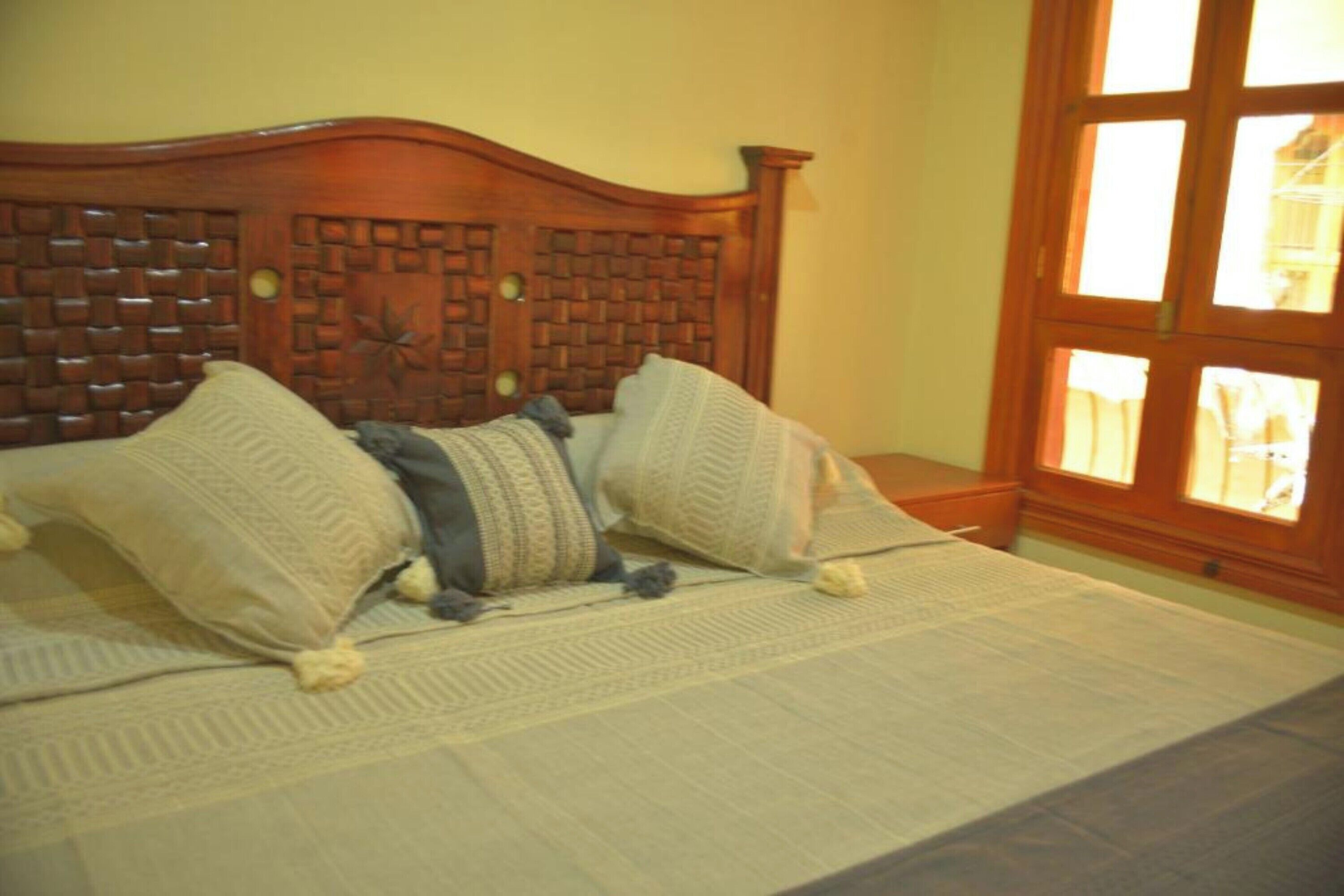 Uma cama com cabeceira de madeira, travesseiros e cobertor.