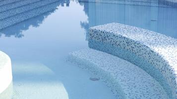 Uma piscina azul límpida com borda azulejada e um dreno no centro.