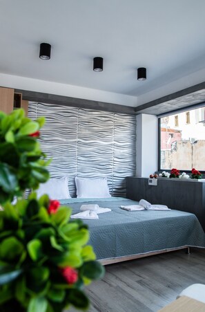 Quarto de hotel moderno com cama, janela e um painel decorativo na parede.