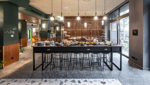 Cozinha moderna com bancada comprida, banquetas e diversos alimentos.