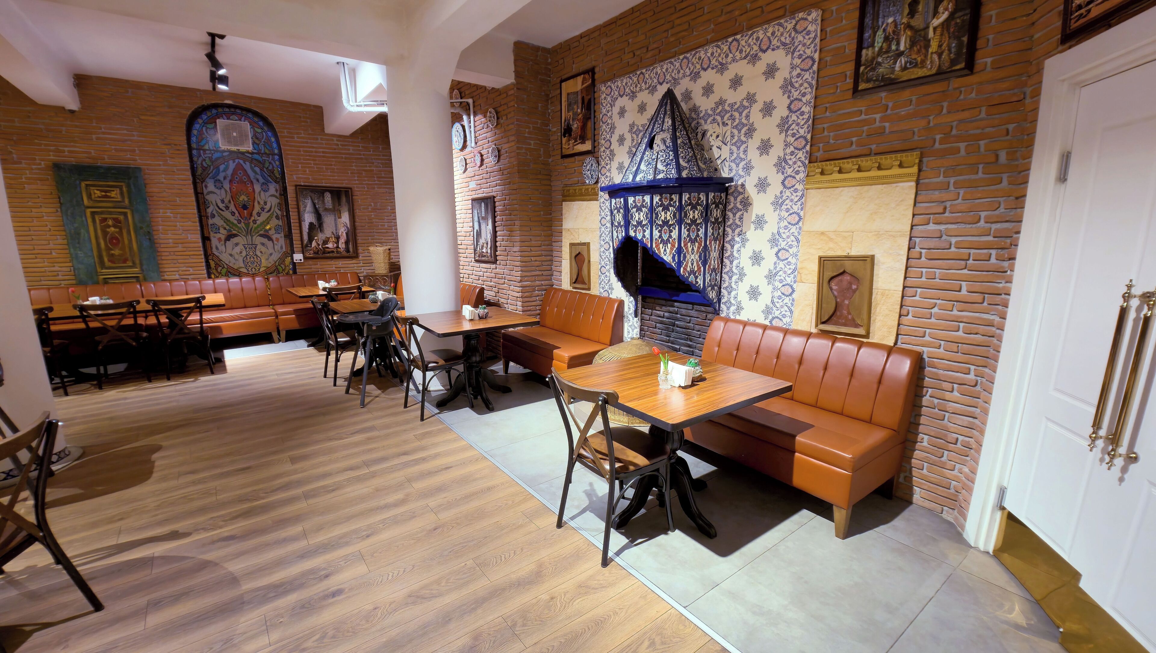 Restaurante com piso de madeira, assentos de couro e paredes de tijolo.