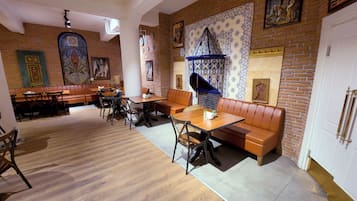 Restaurante com piso de madeira, assentos de couro e paredes de tijolo.