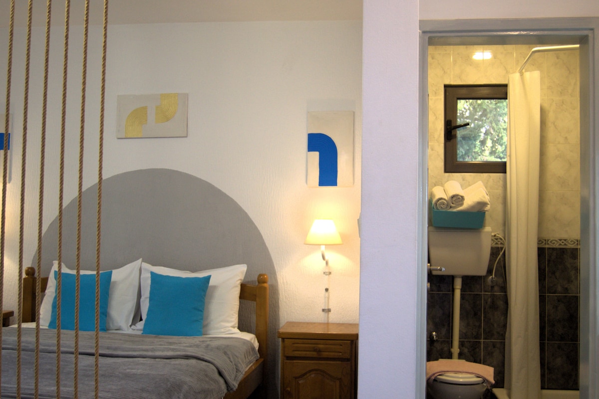 Quarto com cama, mesa de cabeceira e criado-mudo.