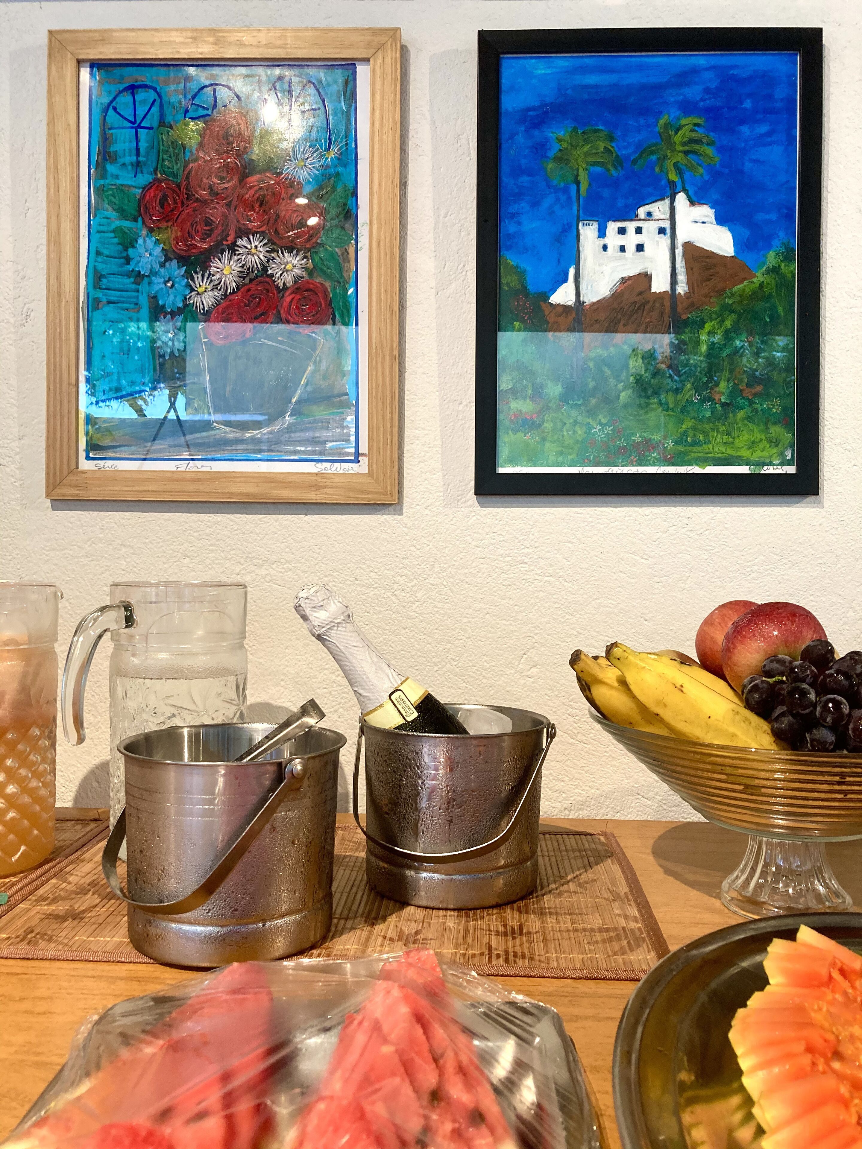 Uma mesa com uma garrafa de champanhe, um jarro e uma cesta de frutas.
