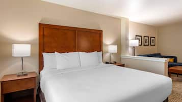 Quarto de hotel com uma cama grande, duas mesas de cabeceira, uma escrivaninha, uma cadeira e um sofá.