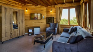Interior em madeira com sofá, poltrona e televisão na parede.