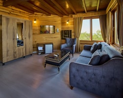 Interior em madeira com sofá, poltrona e televisão na parede.