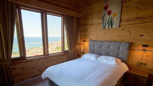 Quarto com uma cama grande, vista para o mar e paredes de madeira.