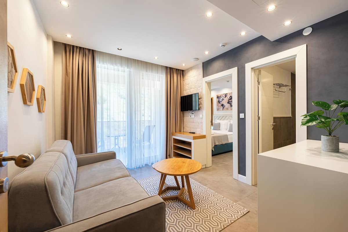 Uma sala de estar moderna com um sofá, uma mesinha de madeira, uma TV e uma planta.