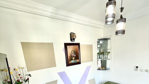 Uma sala de estar com um sofá verde, uma mesa de centro, um tapete estampado com padrão de leopardo e uma decoração de parede em formato de V.