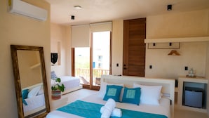 Quarto de hotel com uma cama grande, uma cama menor, um espelho, uma varanda e um minibar.