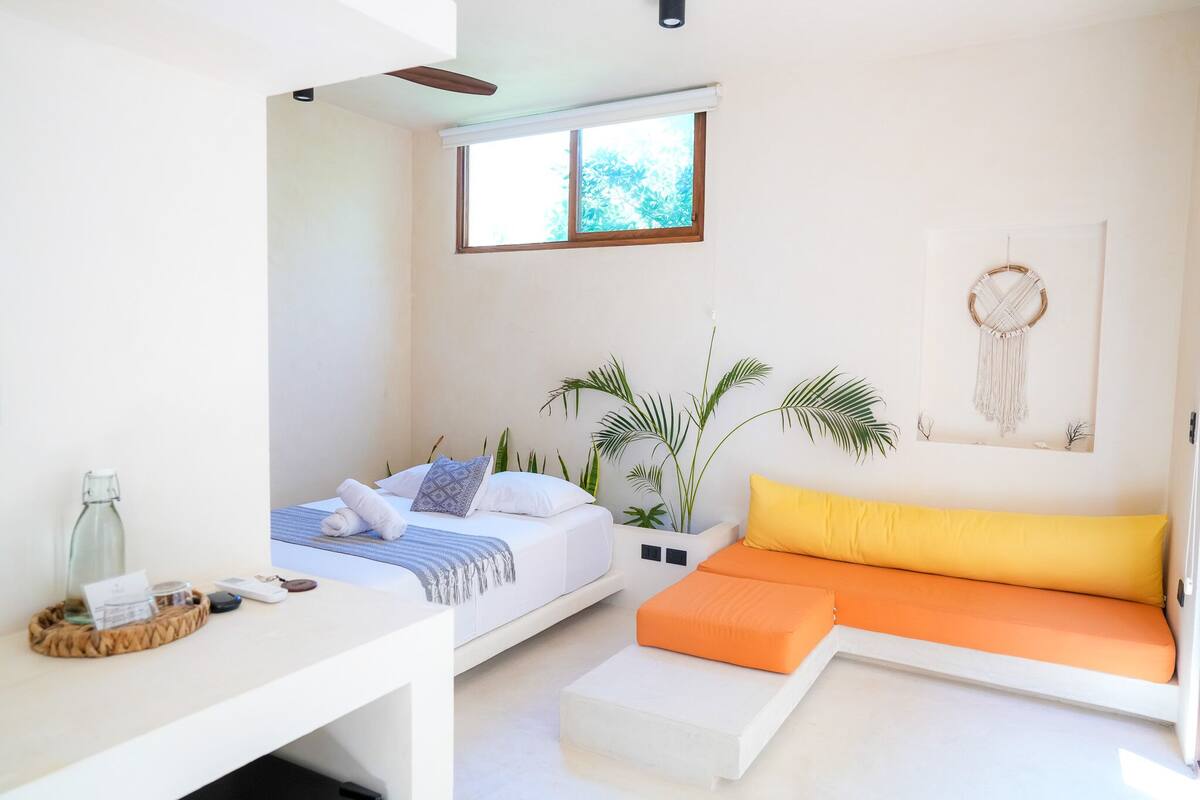 Quarto moderno com cama, sofá, escrivaninha e janela.