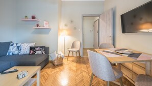 Uma sala de estar moderna com um sofá, uma mesa de jantar e uma televisão.