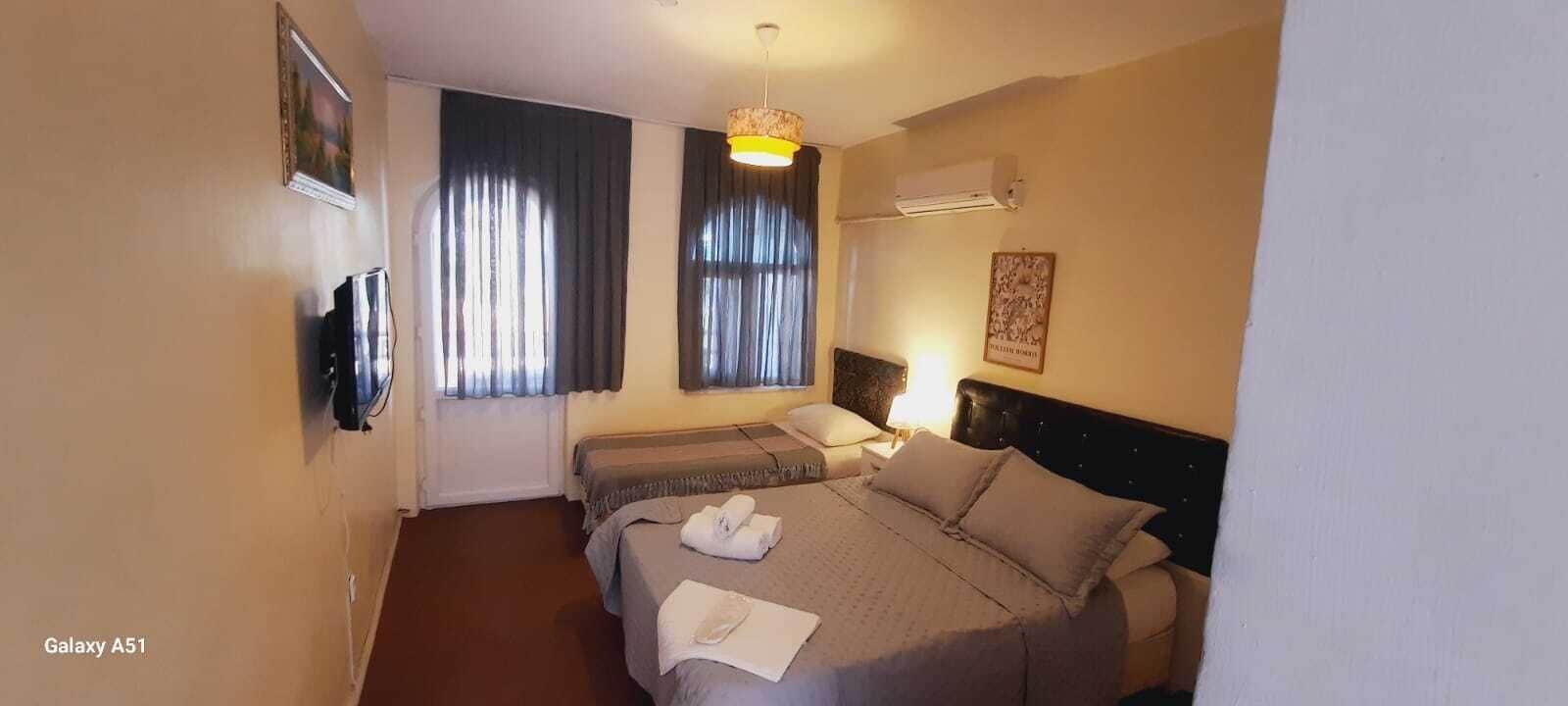 Quarto de hotel com duas camas, televisão, ar condicionado e janela com cortinas.