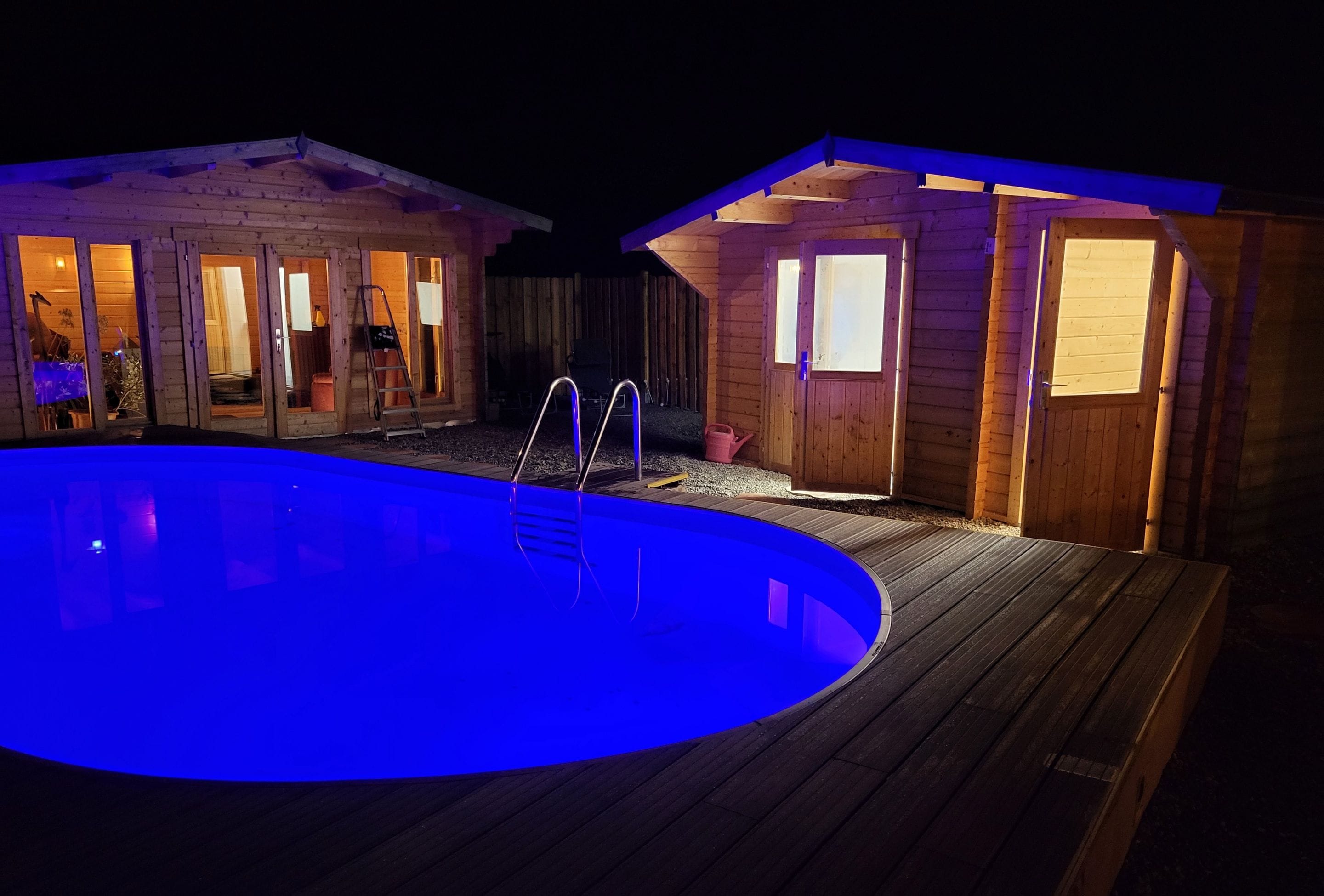 Uma cabana de madeira com piscina, uma escada e uma porta que dá para uma área externa.
