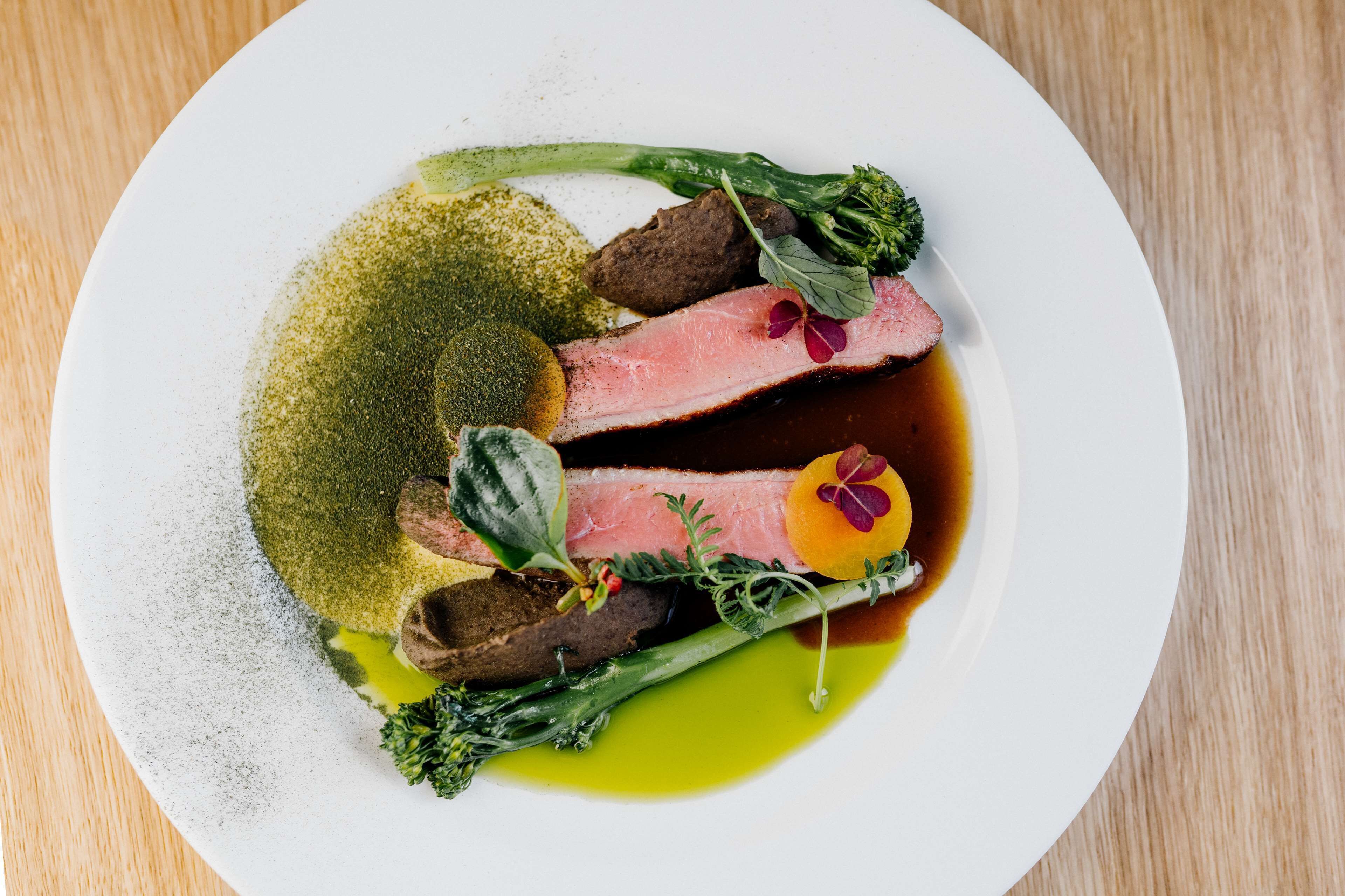 Um prato branco com carne, legumes e molho.