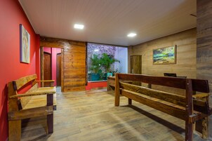Quarto com bancos de madeira, parede vermelha e piso de madeira.