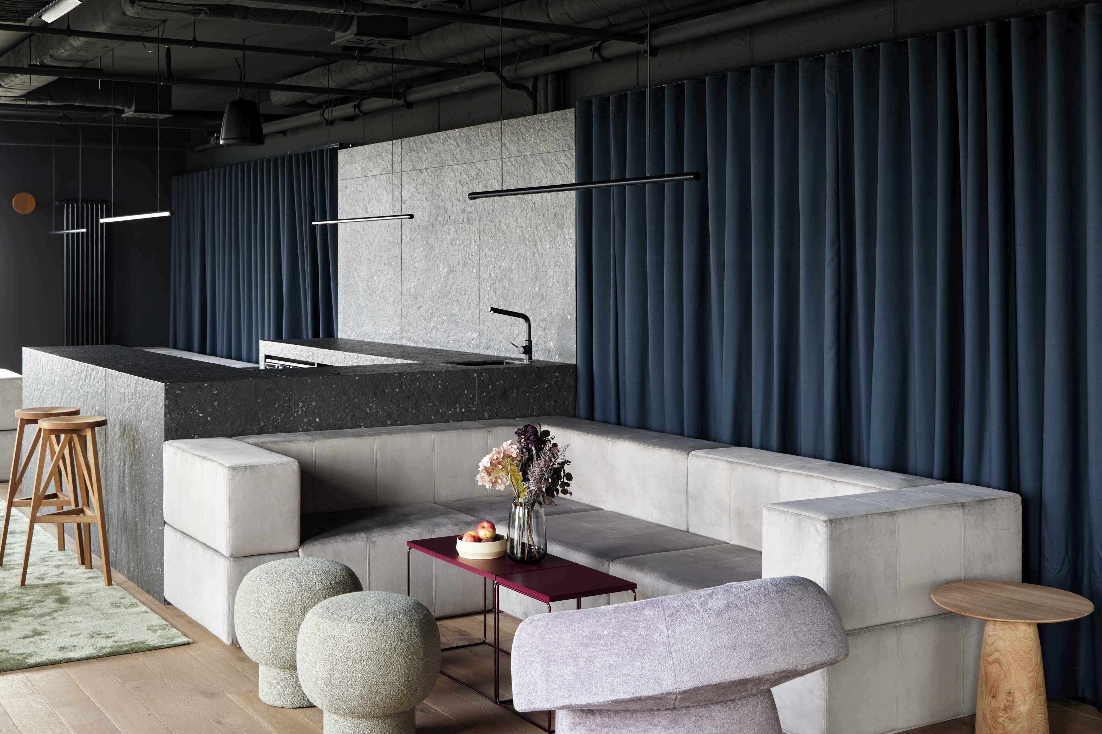 Um interior moderno com um sofá, uma pequena mesa com um vaso e uma área de bar.