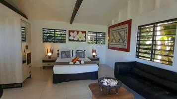 Um quarto com cama, mesas de cabeceira, um sofá preto e uma pequena mesa com objetos decorativos.