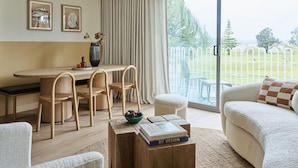 Sala moderna com área de jantar, sofá e vista para um jardim através de uma porta de vidro deslizante.