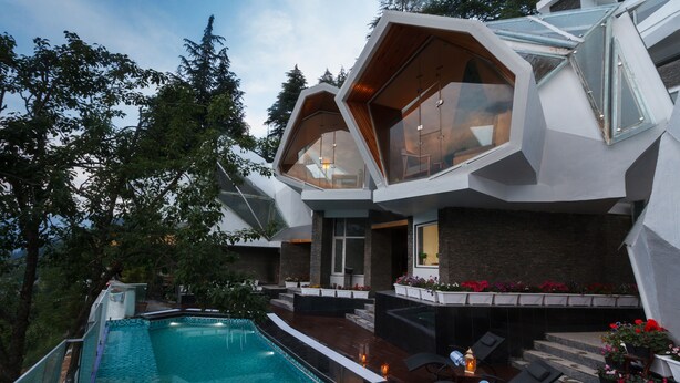 Uma casa moderna com piscina, deck de madeira e grandes janelas.