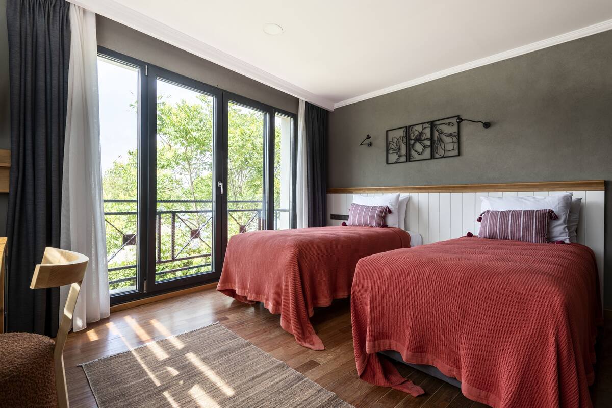 Quarto de hotel com duas camas, uma janela ampla e uma varanda.