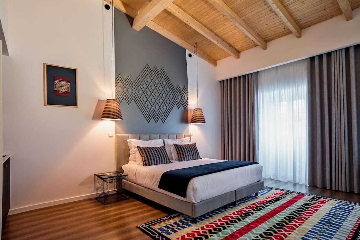 Quarto moderno com uma cama grande, um ornamento de parede geométrico e um tapete estampado.
