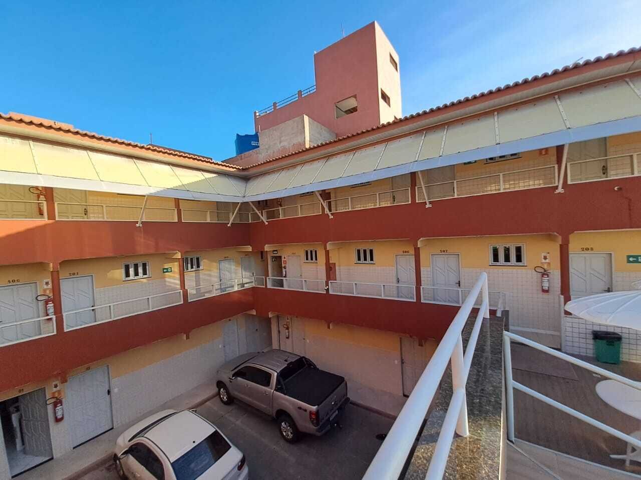 Um estacionamento com várias andares, esquema de cores bege e vermelho, múltiplos níveis e um carro estacionado no nível inferior.