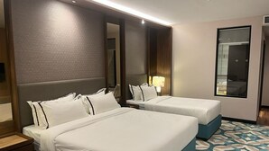 Quarto de hotel com duas camas, um espelho grande, uma mesa de cabeceira e um tapete estampado.