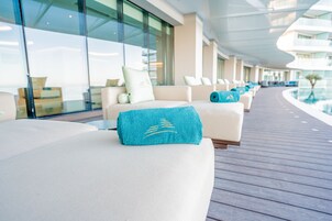 Suíte de hotel moderna com área de piscina, com vários espaços de estar e parede de vidro com vista para a piscina.