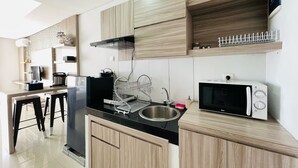 Uma cozinha moderna com armários de madeira, uma pia de aço inoxidável, um micro-ondas e um fogão preto.