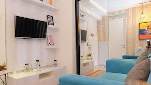 Uma sala de estar moderna com televisão de tela plana, rack branco e sofás azuis.