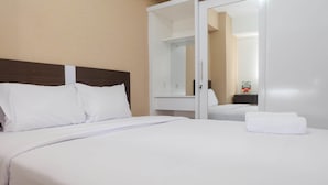 Cama bem arrumada com lençóis brancos, cabeceira de madeira e guarda-roupa branco com espelho.