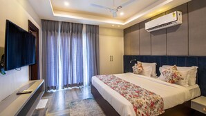 Quarto de hotel moderno com uma cama grande, televisão de tela plana, ventilador de teto e ar condicionado.