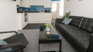 Uma sala de estar moderna com um sofá de couro preto, uma mesa de centro preta e uma pequena planta em vaso.