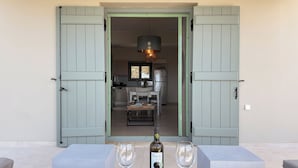 Uma área de refeições com uma mesa posta para dois, uma garrafa de vinho e dois copos.