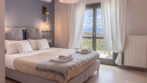 Um quarto moderno com uma cama grande, vista para o exterior e um ventilador de teto.