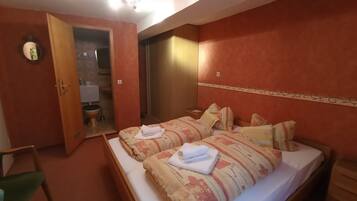 Quarto de hotel com duas camas, um guarda-roupa, uma casa de banho e um espelho.