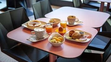 Uma mesa de café da manhã com pratos de comida, um copo de suco de laranja e uma xícara de chá.