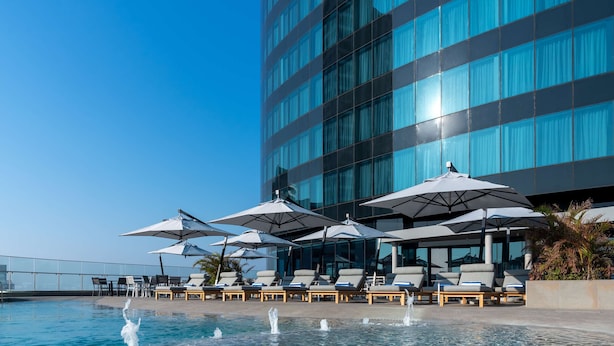 Um hotel moderno com piscina, espreguiçadeiras e guarda-sóis.