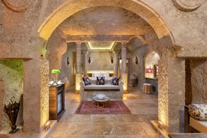 Um interior luxuoso com um arco de pedra, um sofá macio e uma mesa decorativa.