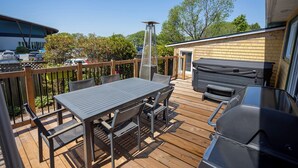 Um deck de madeira com mesa, cadeiras, churrasqueira e ofurô.